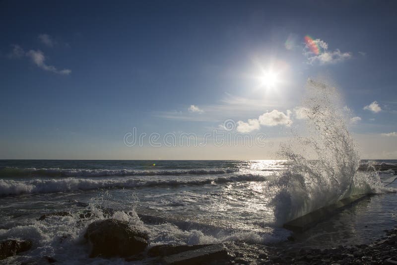 A Wave Rolls Over the Breakwater and Breaks. Foam Takes Off Against the ...