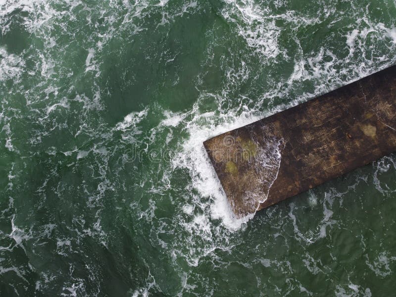 The Wave Rolls Over a Large Square Rock Lying on the Shore, Covered ...