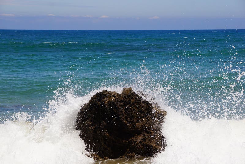 Waves Breaking Onto Rocks with a Blue Ocean Behind Them Stock Photo ...