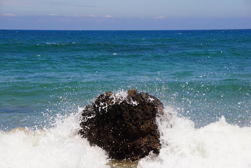 Waves Breaking Onto Rocks with a Blue Ocean Behind Them Stock Image ...