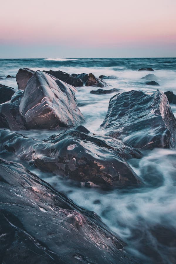 Waves Breaking Over Rocks at the Seaside during a Clear Sunset Stock ...