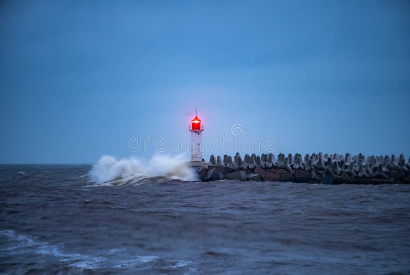 Waves Crash Against the Pier with the Lighthouse with Red Lamp. Baltic ...