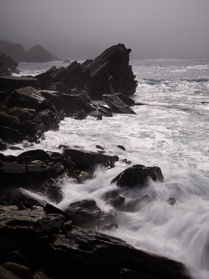 Waves crash against a rock stock photo. Image of rough - 75479212