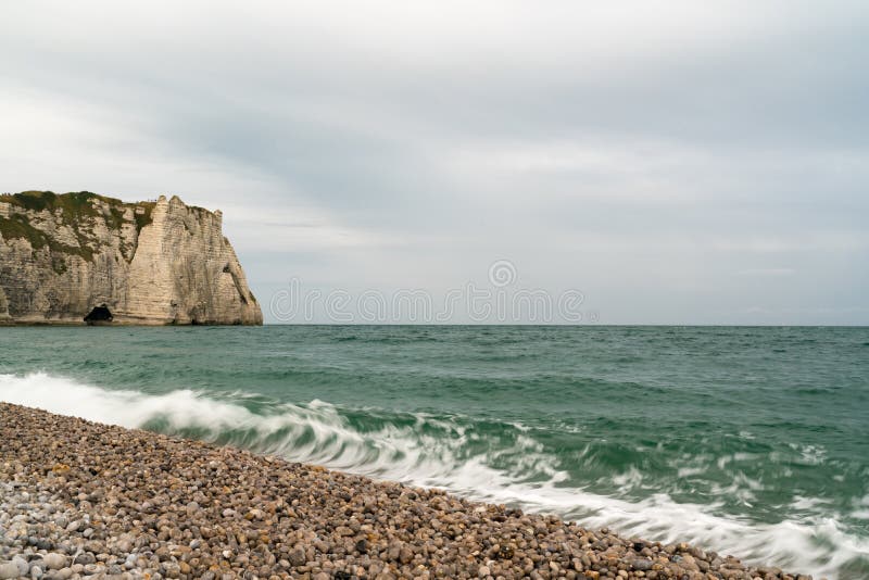 Waves Crash Onto a Rock and Pebble Beach with Jagged Cliffs in the ...