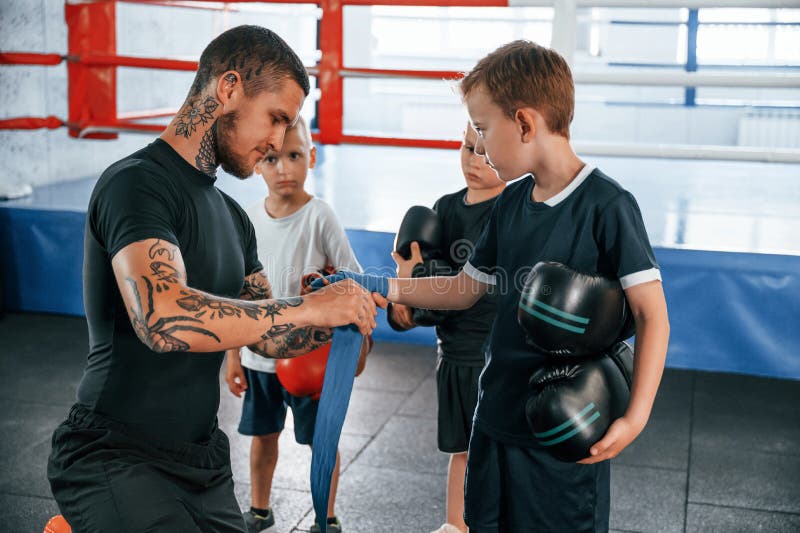 Wearing Blue Hand Wraps. Young Tattooed Coach Teaching the Kids Boxing ...