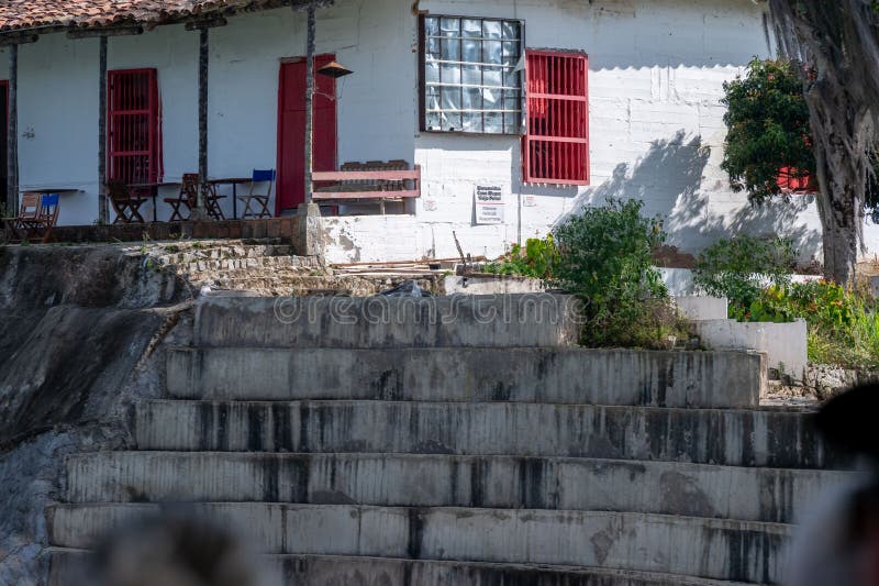 A Weathered Building with Red Accents Sits Overlooking a Tiered Stone ...