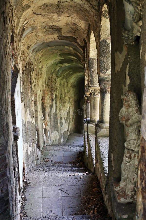 Weathered Stone Corridor Lined with Statues and Flaking Walls in Dim ...