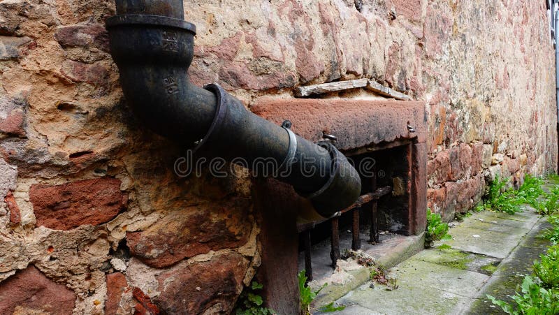 Rusty Pipe Protruding from an Old Stone Wall in an Urban Alleyway Stock ...