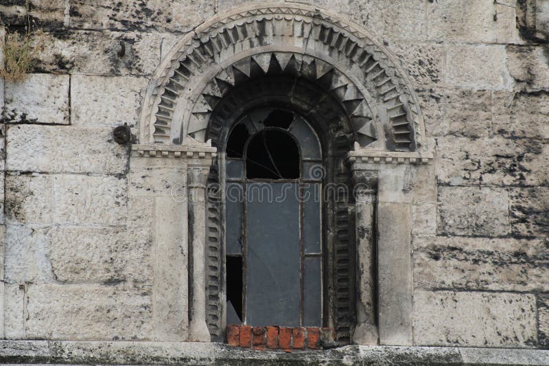 A Weathered Stone Wall Featuring an Arched Window with a Broken Pane in ...