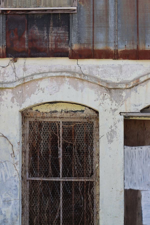 Detail of Abandoned Wood and Concrete Storefront with Arched Rusted ...