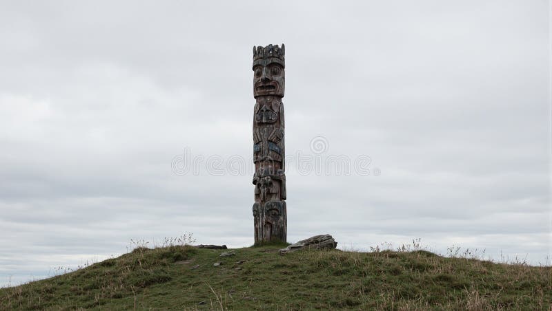 Weathered Totem Pole with Carved Eagles Bears and Wolves on Grassy ...
