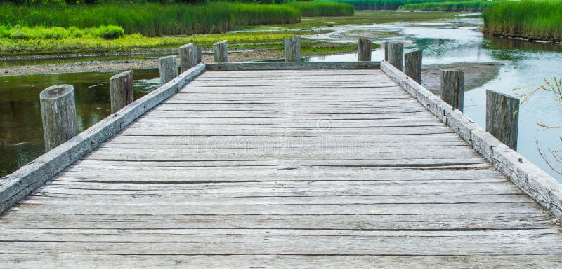 Weathered Wooden Dock Overlooking Shallow River and Marshland Stock ...