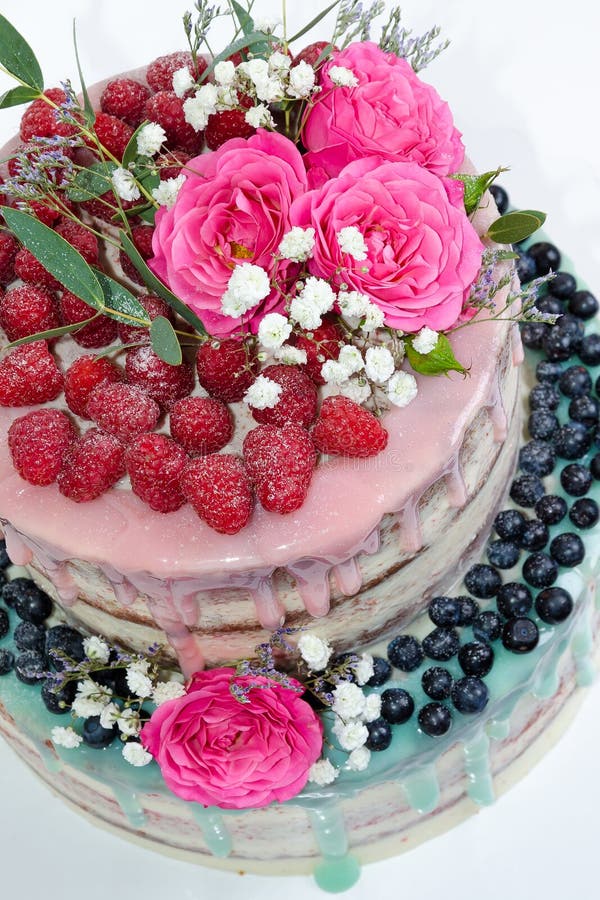 A Wedding Color Drip Cake with Roses, Blueberries and Raspberries Stock ...