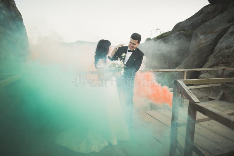 Wedding Couple Posing Near Rocks with Colored Smoke Behind Them Stock ...
