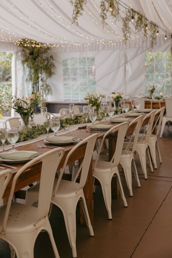 Wedding Reception Setup with Long Tables, White Chairs, and Floral ...