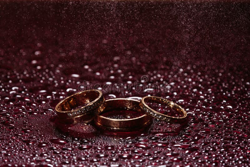 Wedding Rings on Dark Water Surface Shining with Light. Rain, Water ...