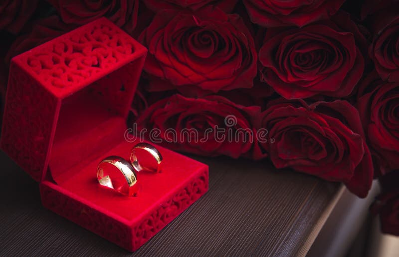 Wedding rings on red roses stock photo. Image of flower - 129313400