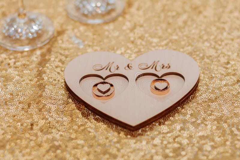 Wedding Rings on a Wooden Stand Standing on a Table Covered with Gold ...