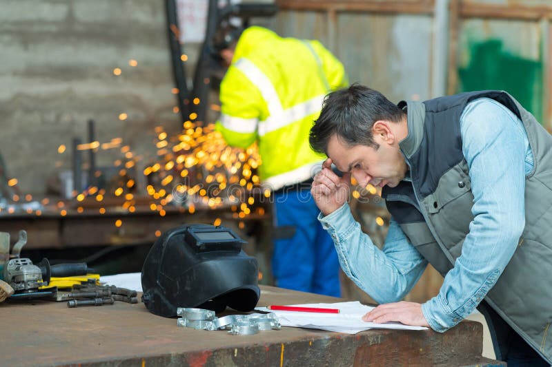 Welder looking at paper stock image. Image of skilled - 279542303