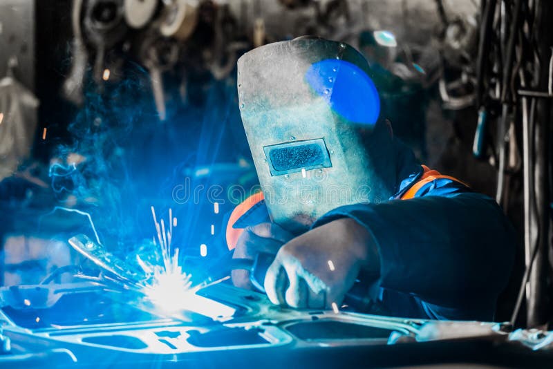 Welder Man in a Protective Mask of Iron is Engaged in the Process of ...