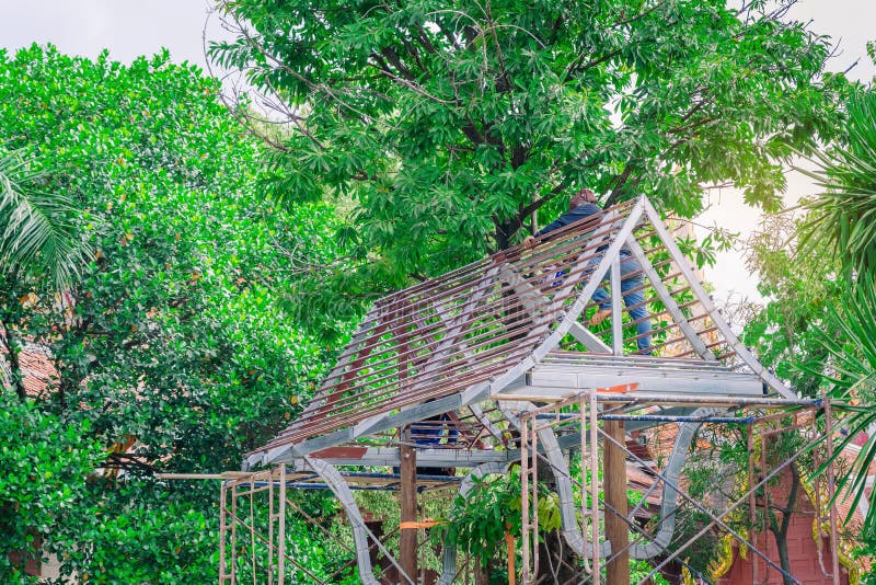 Welder and Painter are Helping To Build a Gable Roof Structure Below a ...