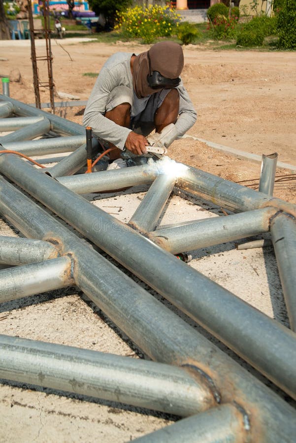 The Welder is Sitting on the Steel Roof Frame and is Welding. Stock ...