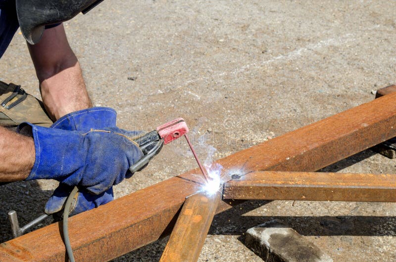 Welder at Work Weld an Iron Construction in a Metal Warehouse. Stock ...