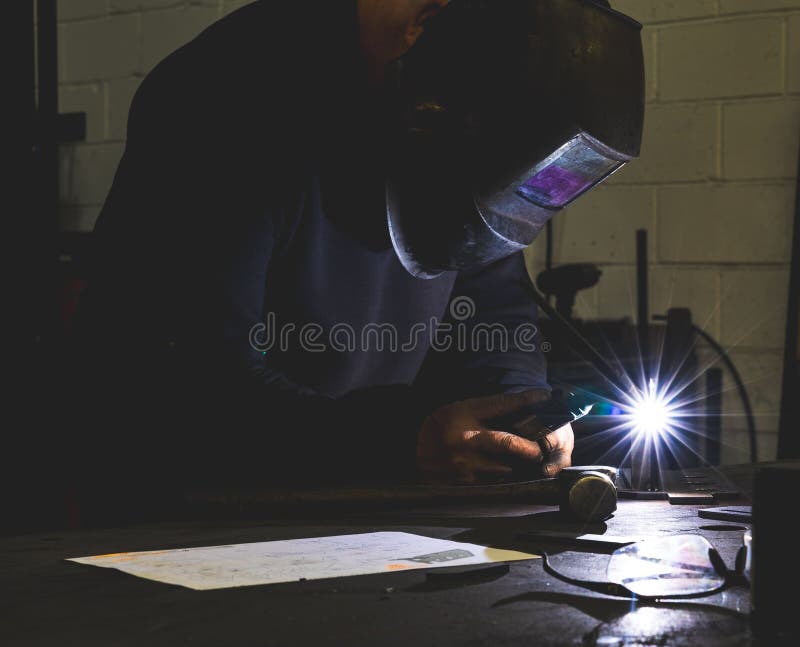 Welder Working in a Dimly Lit Workshop with Bright Welding Spark. Stock ...