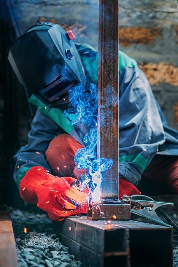A Welder Welds a Metal Pole with Electric Welding, Holds an Electrode ...