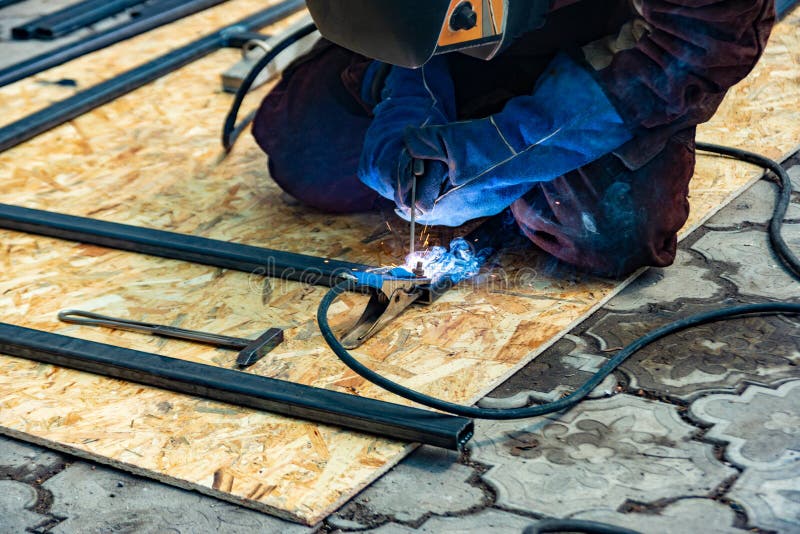 A Welder at Work Assembles a Metal Structure from a Shaped Pipe Stock ...