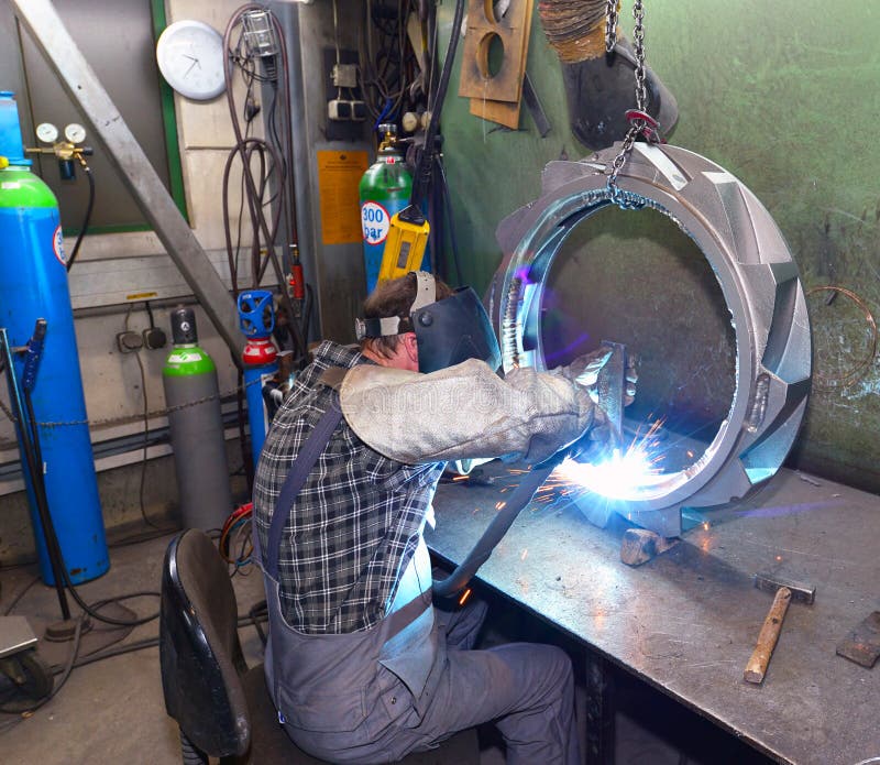 Welder at a Workplace in Metal Construction Working on a Workpiece Made ...