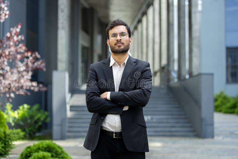 A Sharply Dressed Businessman Poses with Crossed Arms in Front of a ...