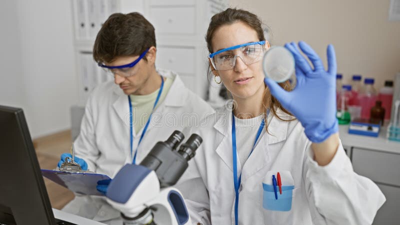 In a Well-equipped Lab, a Woman and a Man in Lab Coats Analyze Samples ...