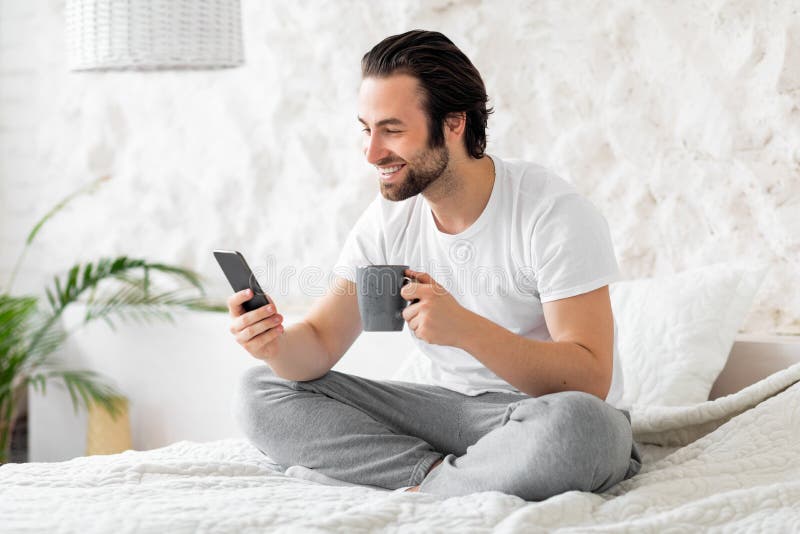 Well-rested Handsome Guy Chilling on Bed at Home, Using Smartphone ...