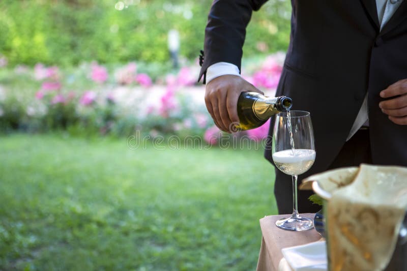 A Welldressed Man in a Suit is Elegantly Pouring Champagne into a Glass ...