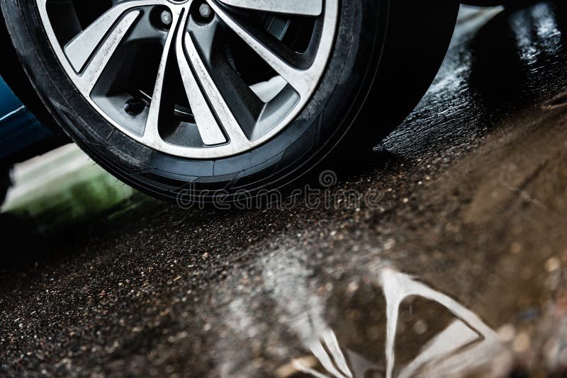 Wet Asphalt with Reflection of Car Wheel in Puddle. Stock Image - Image ...