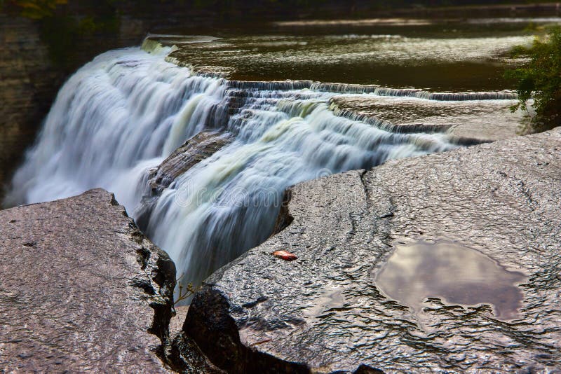 Wet Rocks in Foreground by Huge Waterfall Pouring Over Cliffs Stock ...