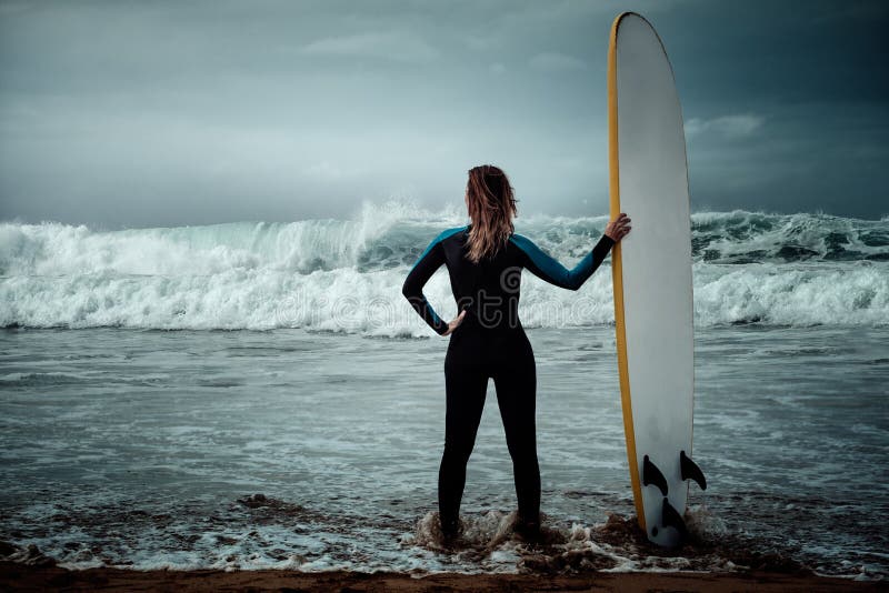 Femme Dans Le Wetsuit Tenant Une Planche De Surf Sur La Plage Photo
