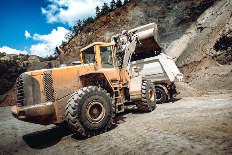 Backhoe Loading Ground into a Dump Truck on Construction Site. Birds ...