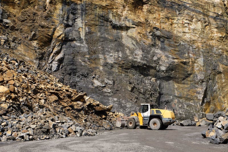 A Wheel Loader Machine Working on a Large Heap of Stones in Front of a ...