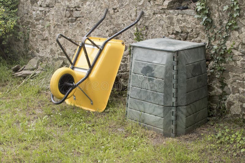 Wheelbarrow and Plastic Compost Bin in Home Garden in Sunny Day Stock ...