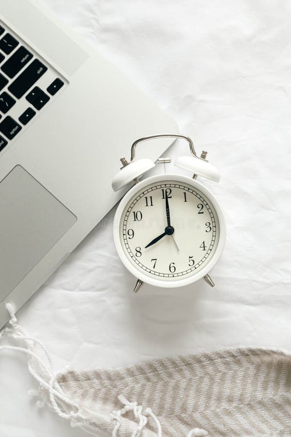 White Alarm Clock and Laptop on a White Bed, Top View. Stock Photo ...