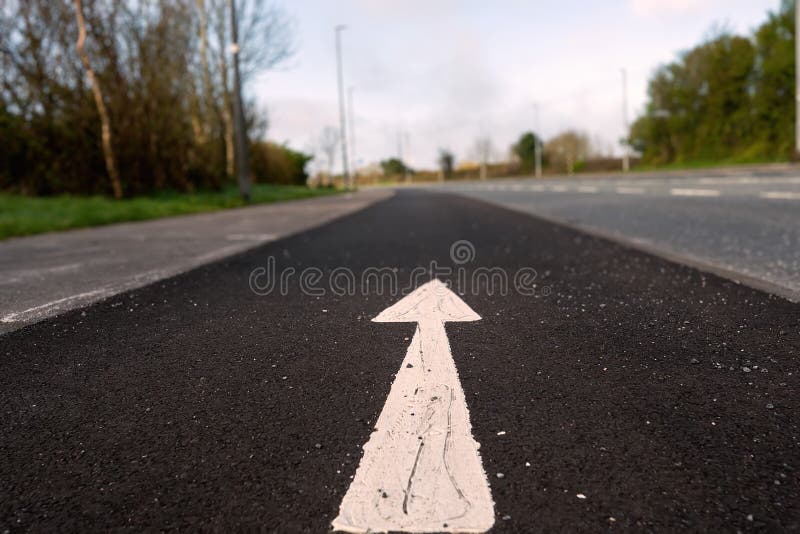 White Arrow on a Black Asphalt Surface in Focus. Direction Sign on a ...