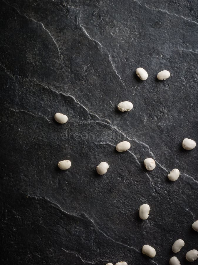 White Beans are Scattered Randomly on a Black Stone Table from Slate ...