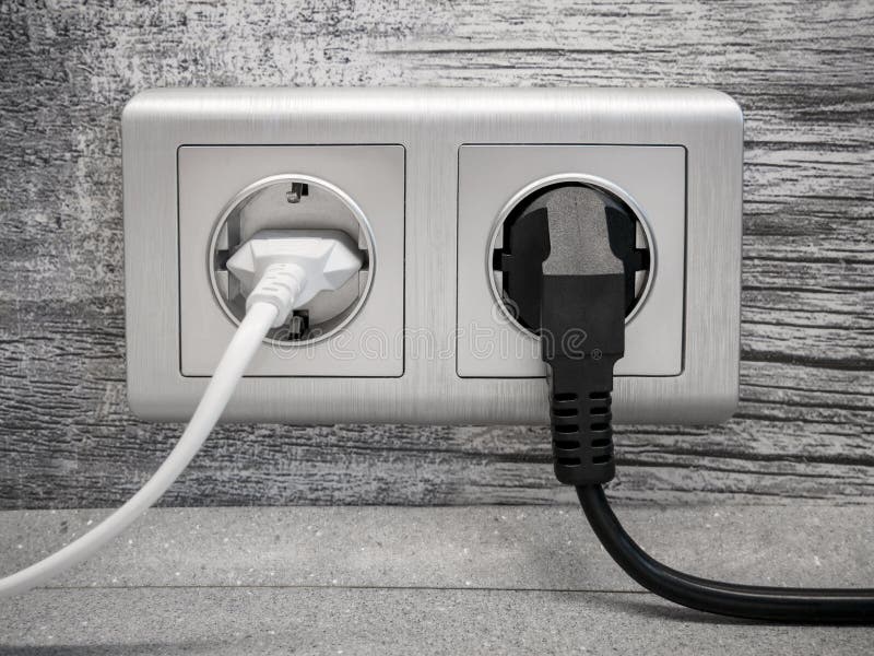 A White and Black Electric Plug with a Cable in a Wall Outlet. an ...