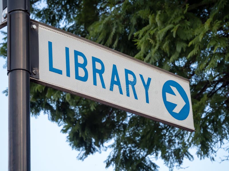 White and Blue Library Sign with Arrow in Front of Tree and Sky Stock ...