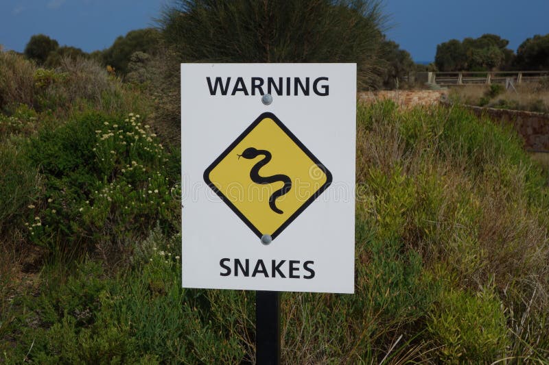 White Board with a Yellow Sign Warning about Snakes in a Green Area ...