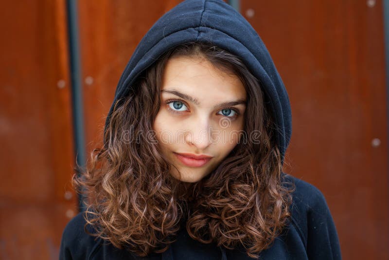 White Brunette Teenage Girl With Curly Hair Poses On The Street In The