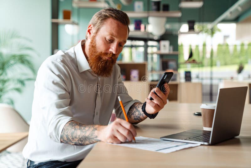 White Business Man Writing Down Notes while Working on Laptop in Office ...