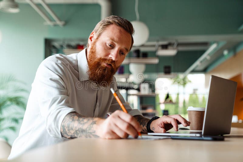 White Businessman Writing Down Notes while Working on Laptop in Office ...
